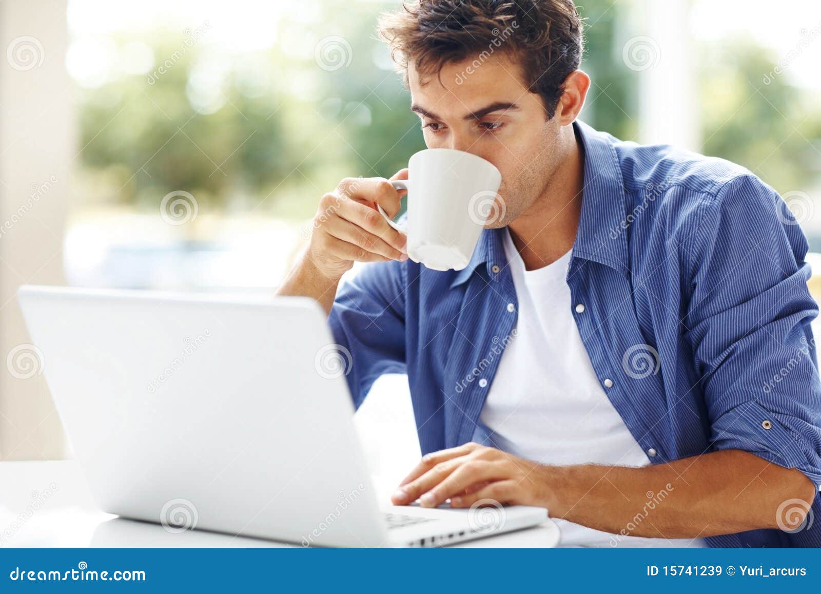 Young Man Drinking Coffee while Looking at Laptop Stock Image - Image ...