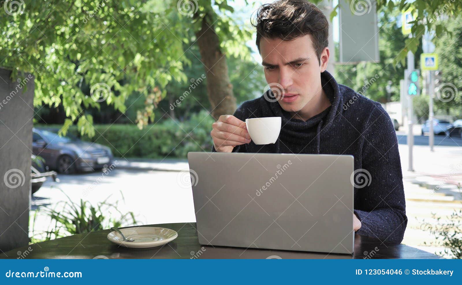 Young Man Drinking Coffee while Working on Laptop in Cafe Terrace Stock ... Young Man Drinking Coffee while Working on Laptop in Cafe Terrace Stock ...
