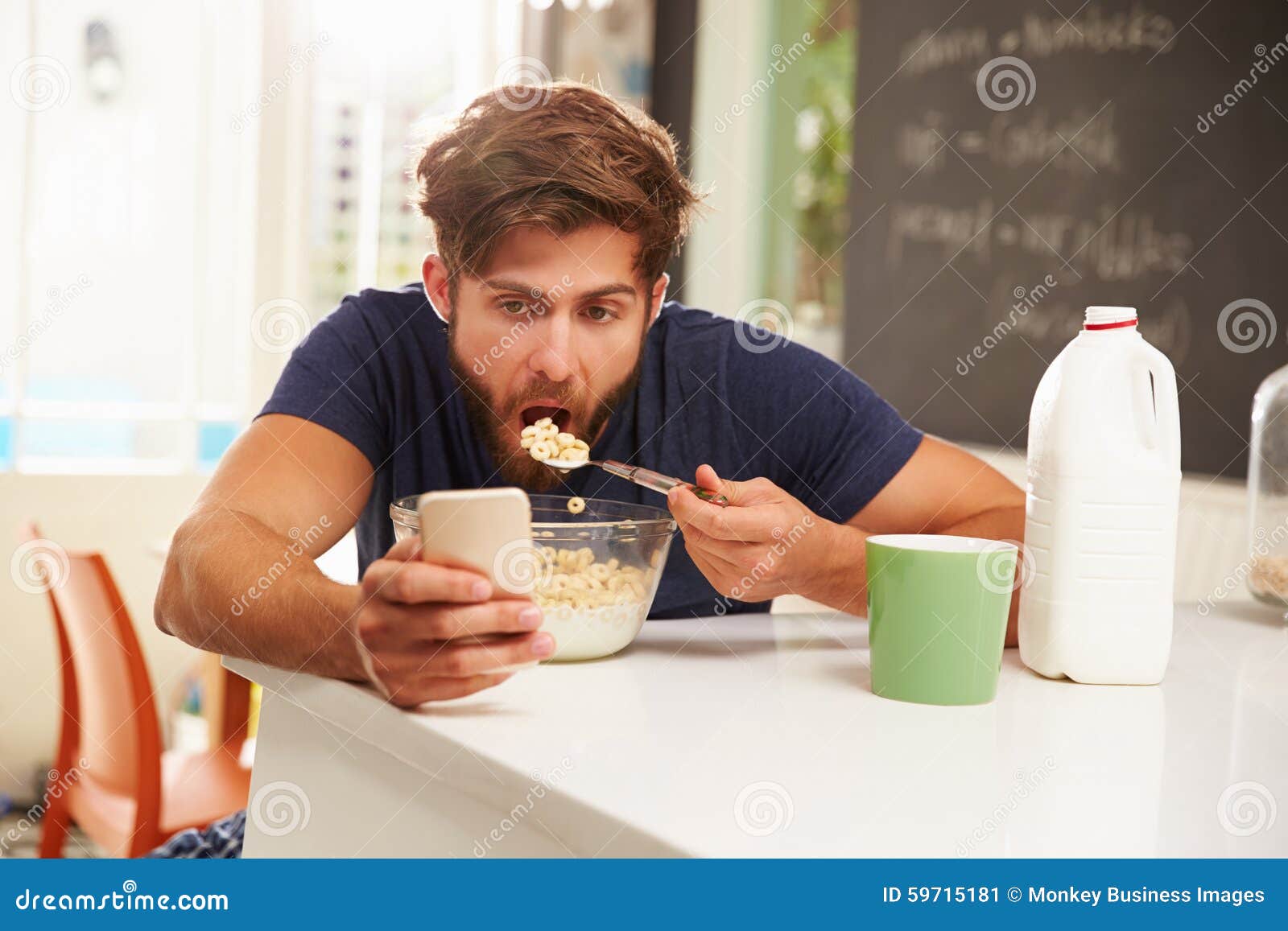 Young Man Eating Breakfast Whilst Using Mobile Phone Stock Image ...