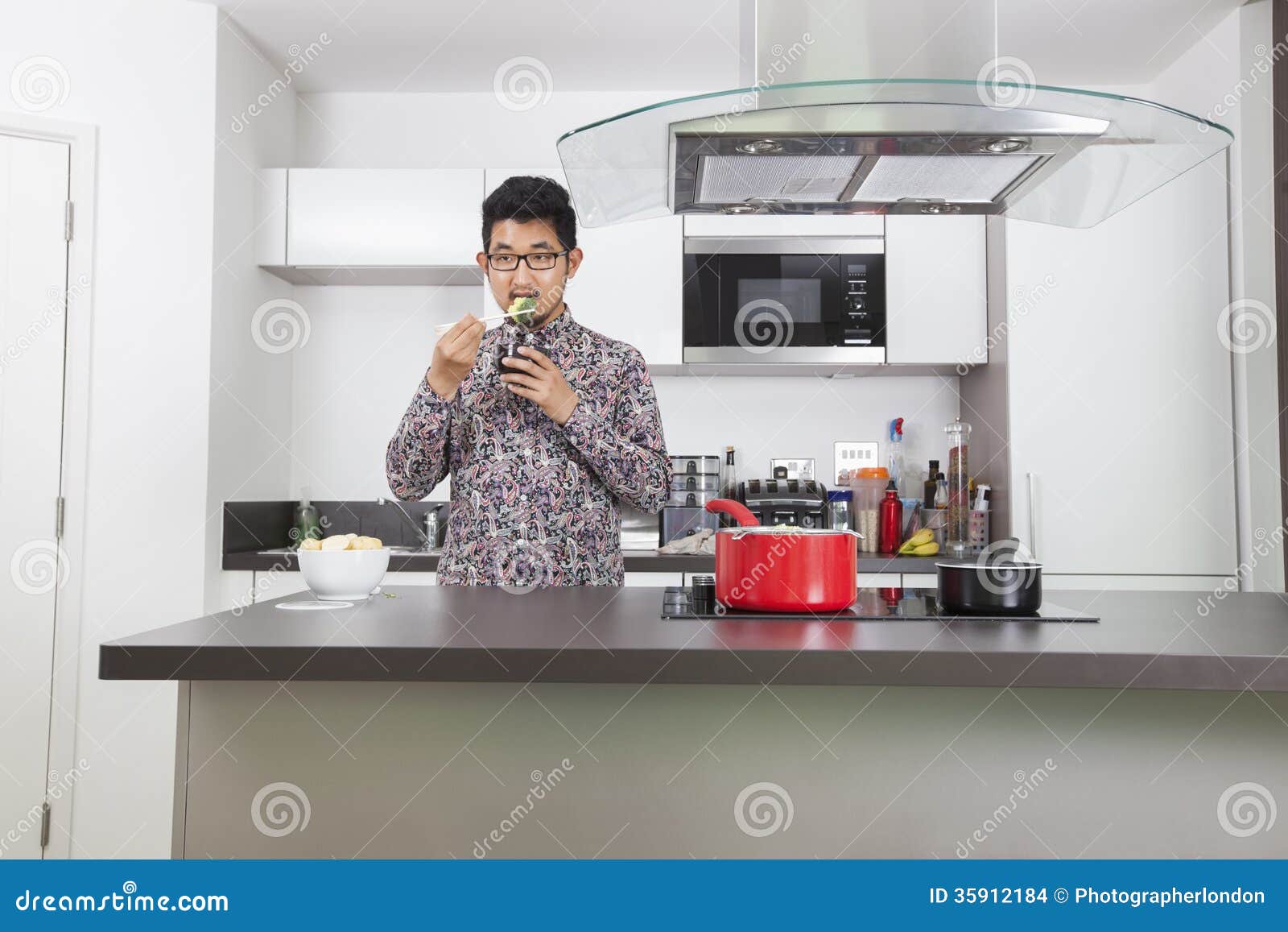 Young Man Eating Broccoli at Kitchen Counter in Home Stock Photo ...