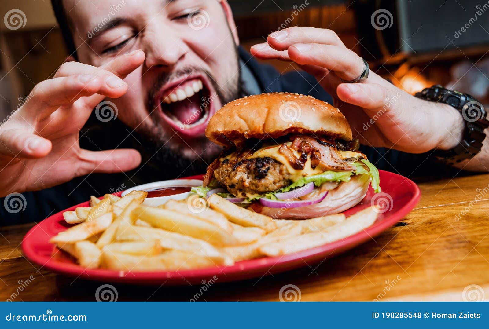 Young Man Eating a Cheeseburger. Restaurant Background. Stock Photo ...