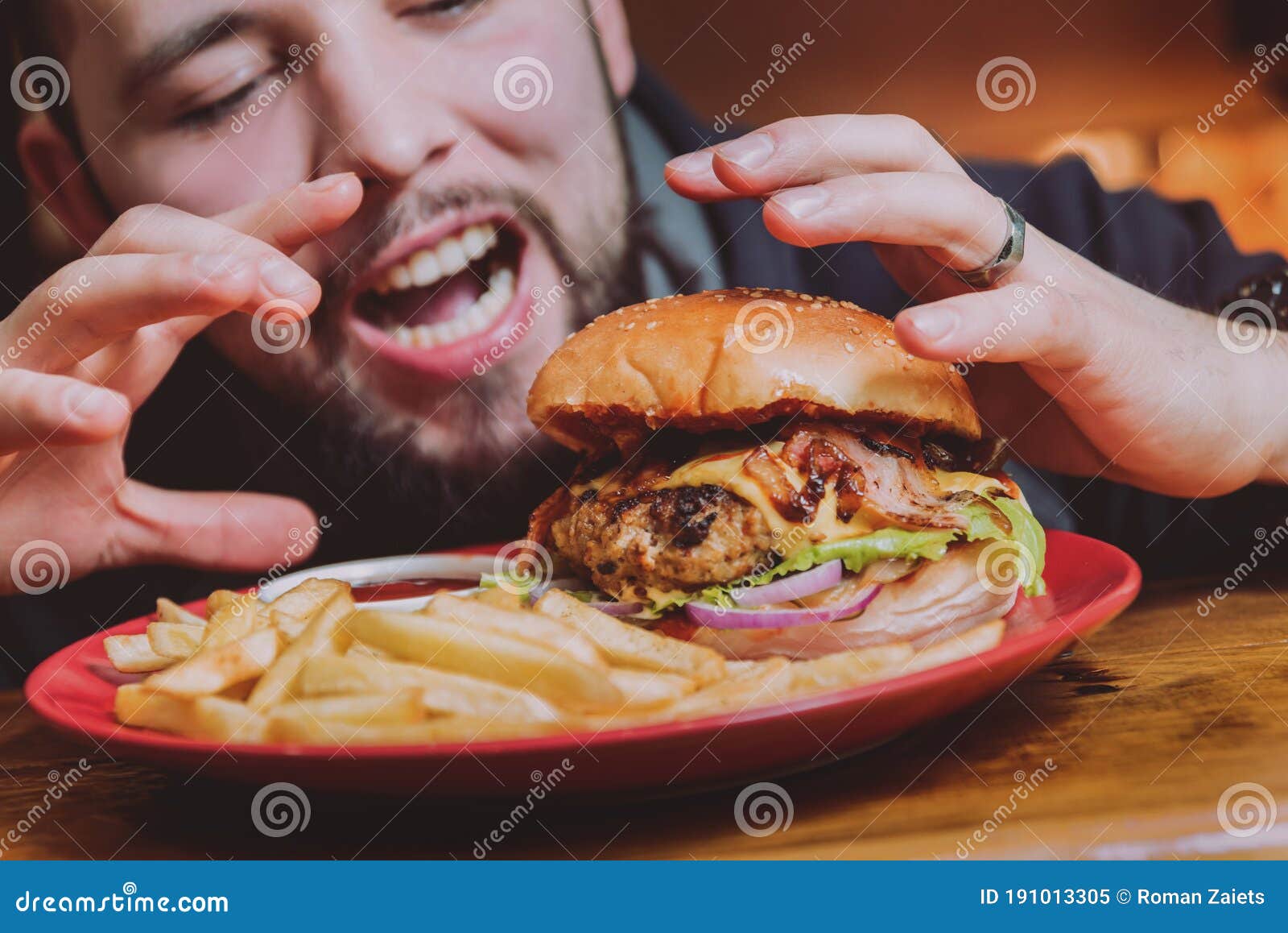 Young Man Eating a Cheeseburger. Restaurant Background. Stock Image ...