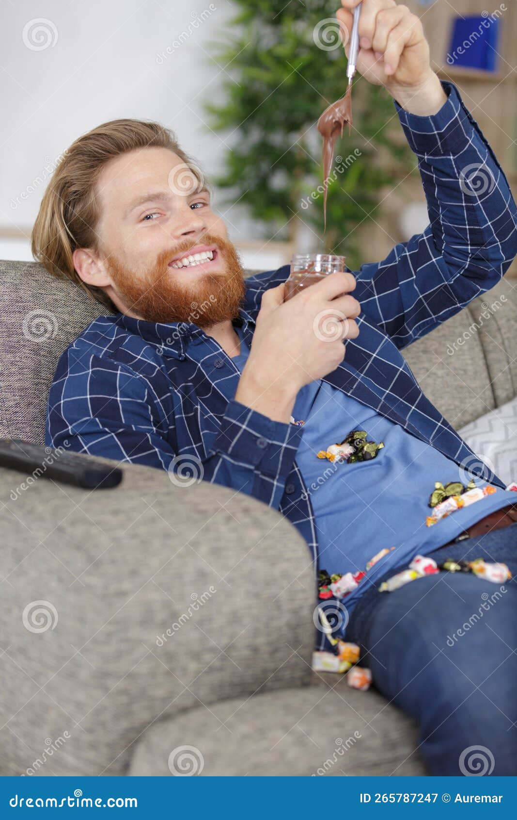Young Man Eating Chocolate while Sitting on Sofa at Home Stock Image ...