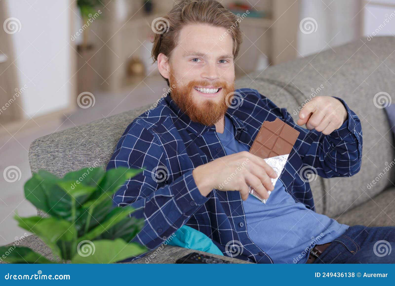 Young Man Eating Chocolate on Sofa Stock Photo - Image of eating, male ...