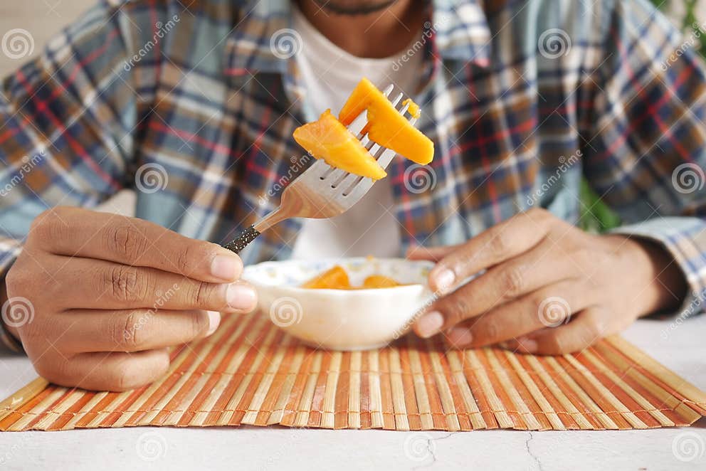 Young Man Eating Mango while Sited Stock Photo - Image of eating, slice ...