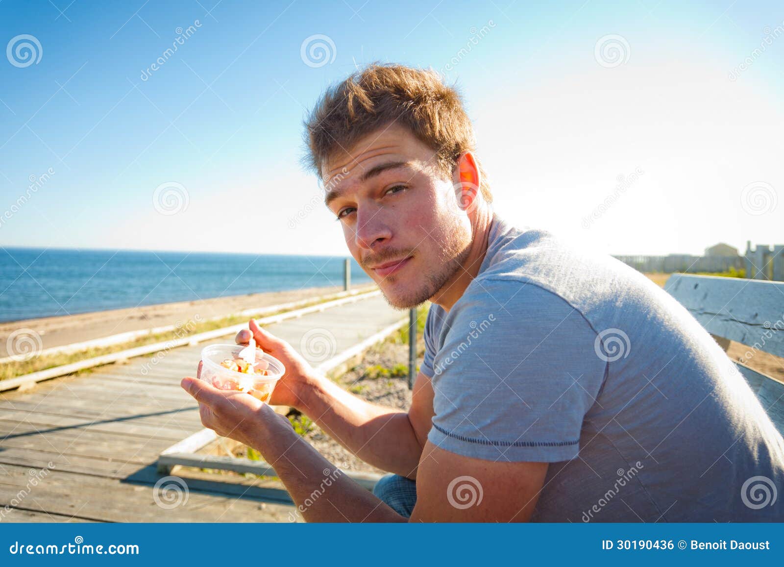 Young Man Eating on the Beach Stock Photo - Image of sitting, resort ...