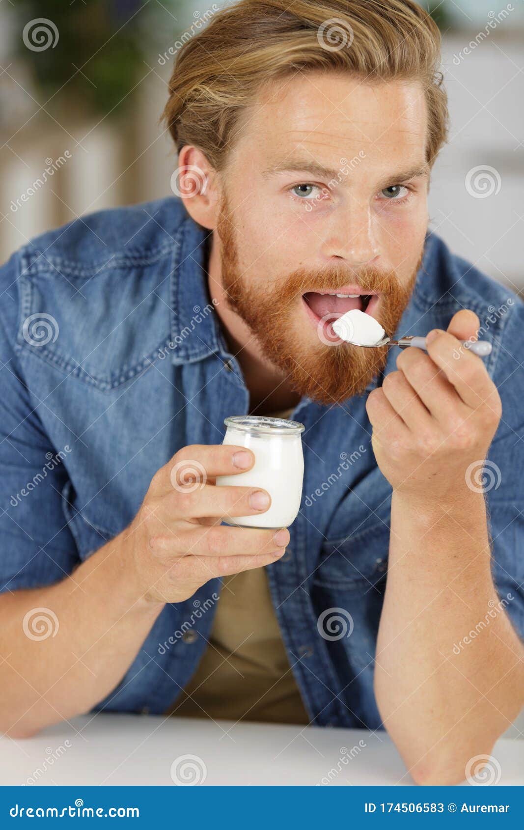Young man eating yogurt stock image. Image of smile - 174506583