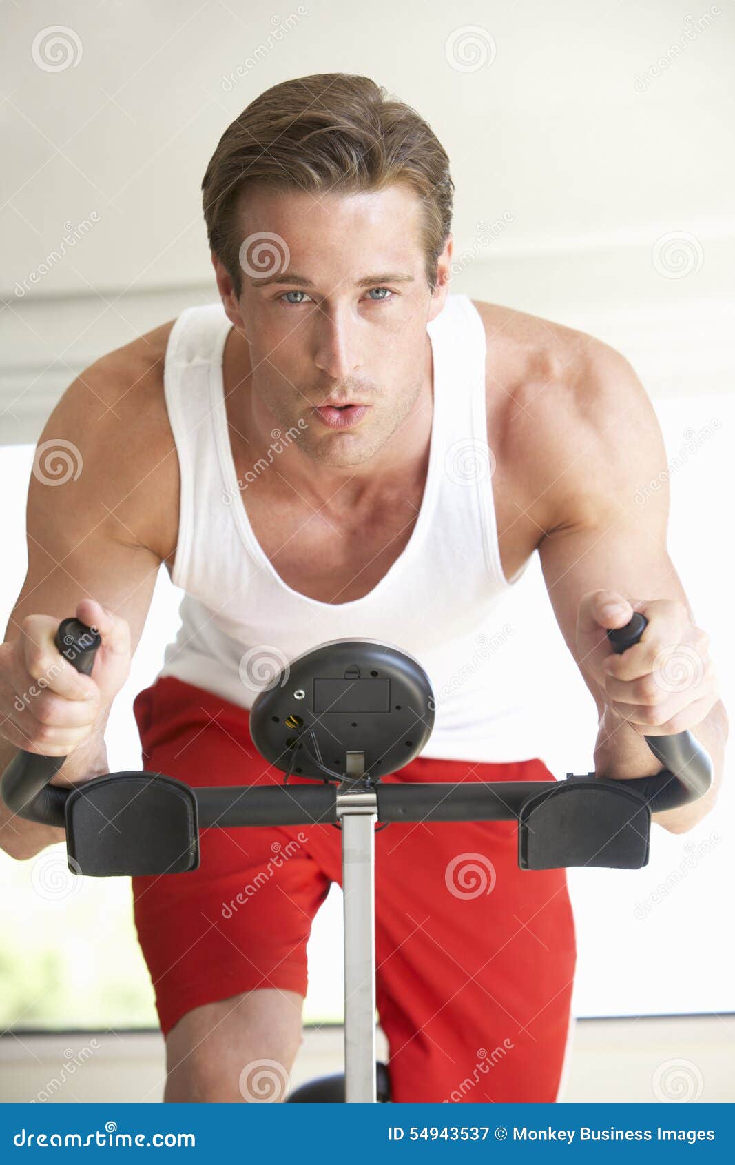 Young Man on Exercise Bike stock image. Image of exercising - 54943537