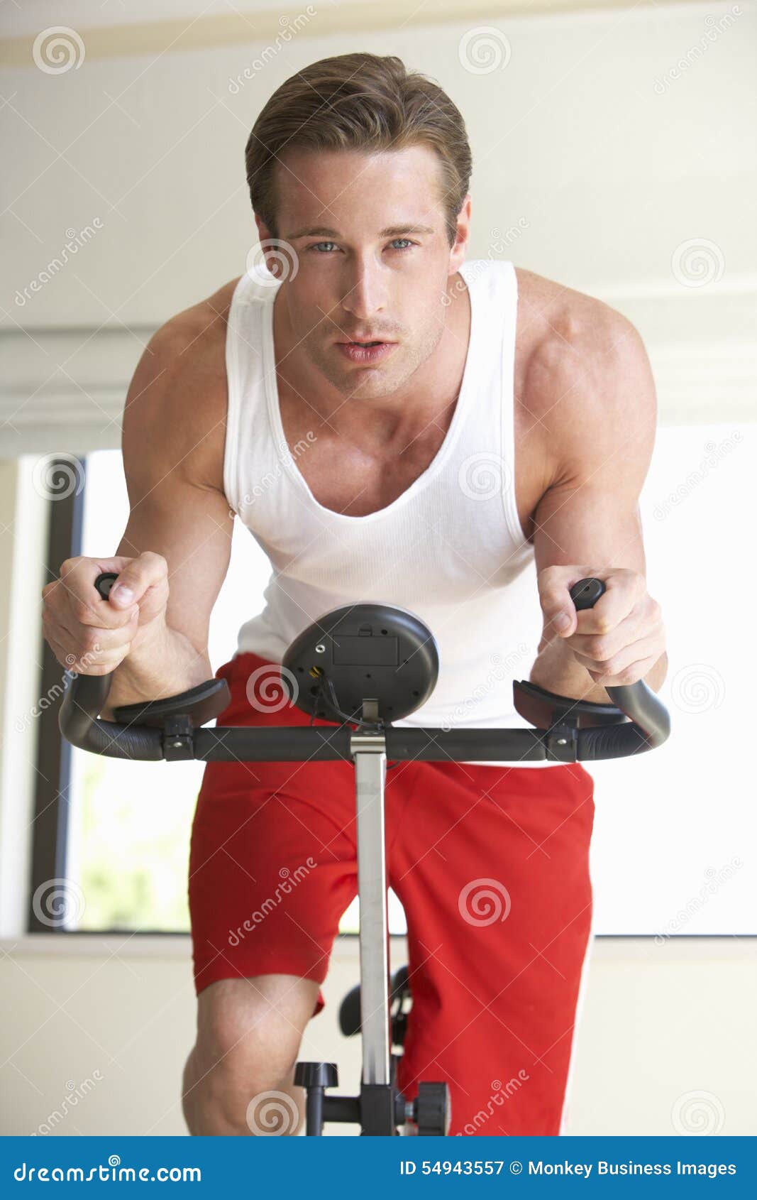 Young Man on Exercise Bike stock image. Image of exercising - 54943557