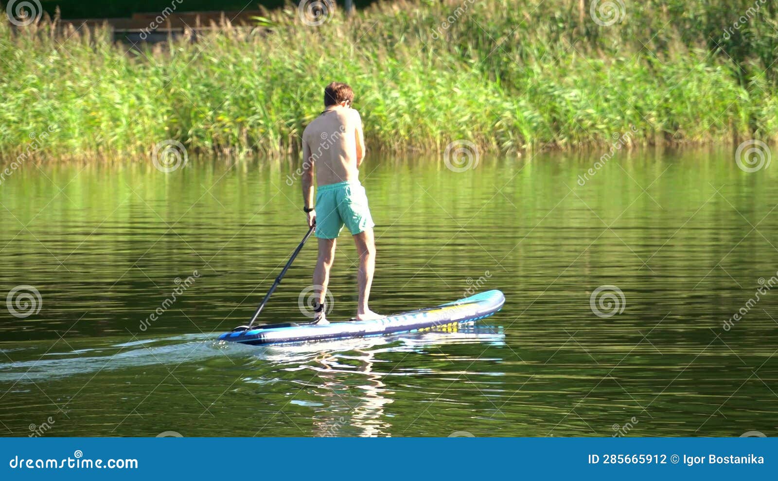Young Man Floating Down a River Standing on a Supboard Stock Footage ...