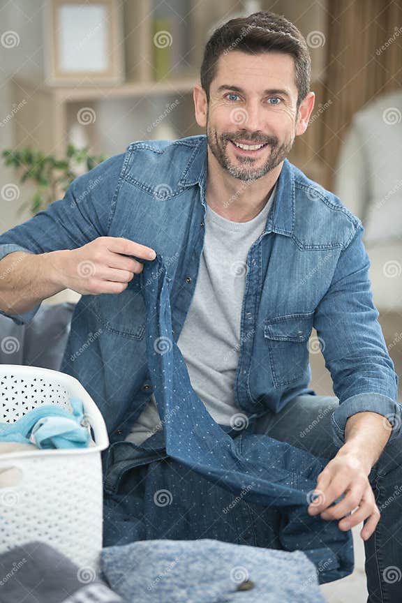 Young Man Folding Laundry on Sofa Stock Photo - Image of couch ...