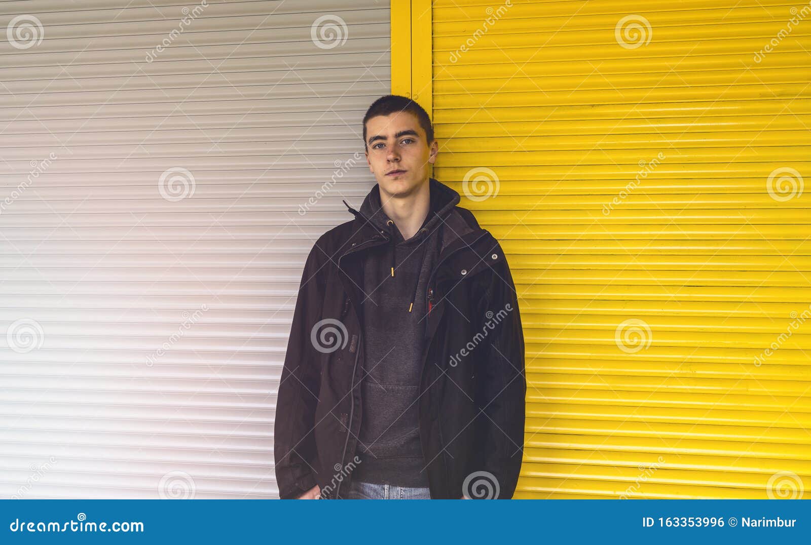 Young Man in Front of a Yellow and Gray Roller Shutter Stock Photo ...