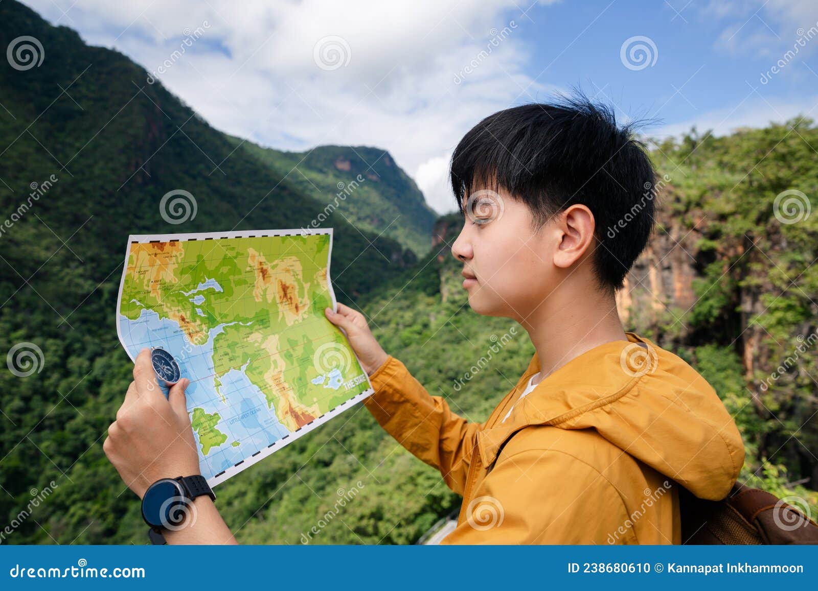 A Young Man Hiking in Forest Looking at a Map and Using a Compass Stock ...