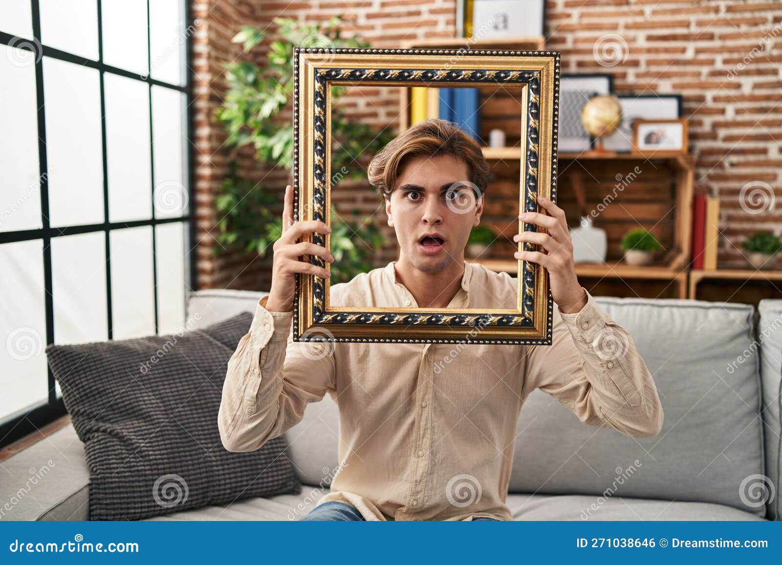 Young Man Holding Empty Frame in Shock Face, Looking Skeptical and ...