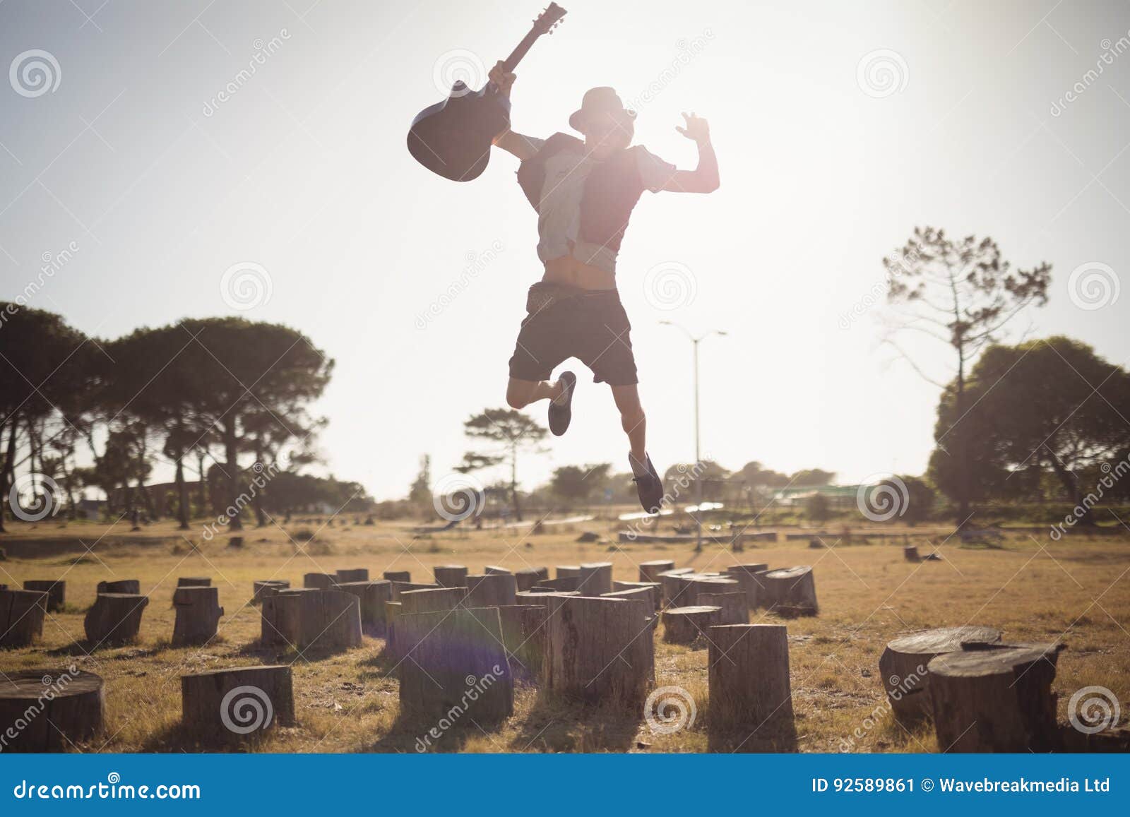Young Man Holding Guitar while Jumping on Tree Stump Stock Image ...