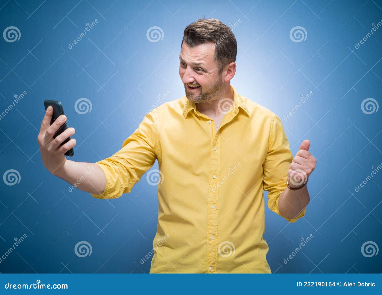 Young Man Holding In Hands Smartphone And Making Selfie While Showing V