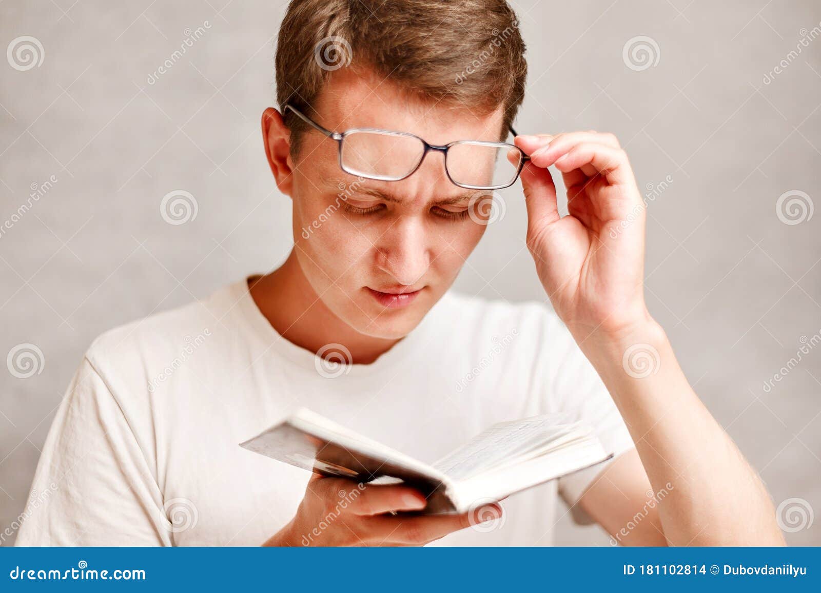 The Young Man Holds Glasses with Diopter Lenses and Looking at the Book ...