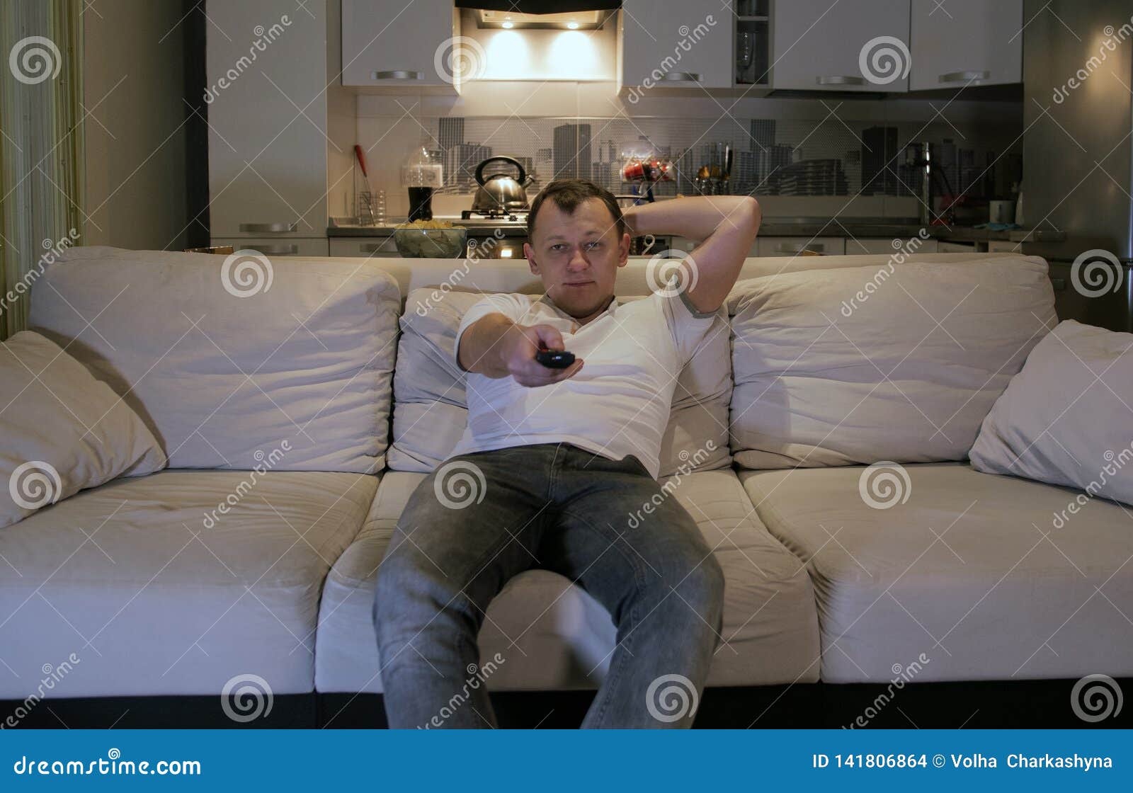 A Young Man at Home Sitting on a Sofa in the Evening with the Remote ...