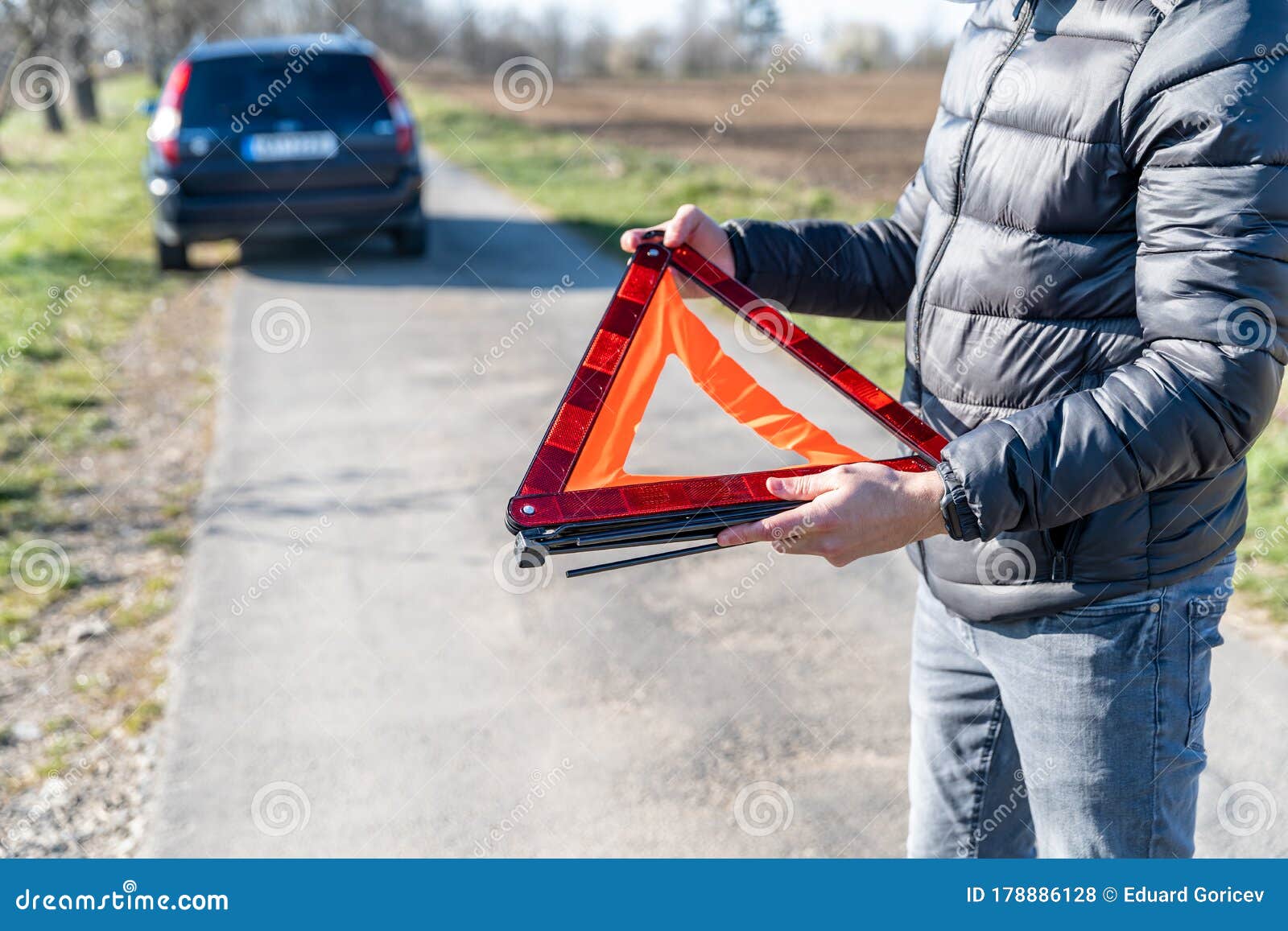 Young Man Installs an Orange Warning Triangle on the Road in Front of a ...