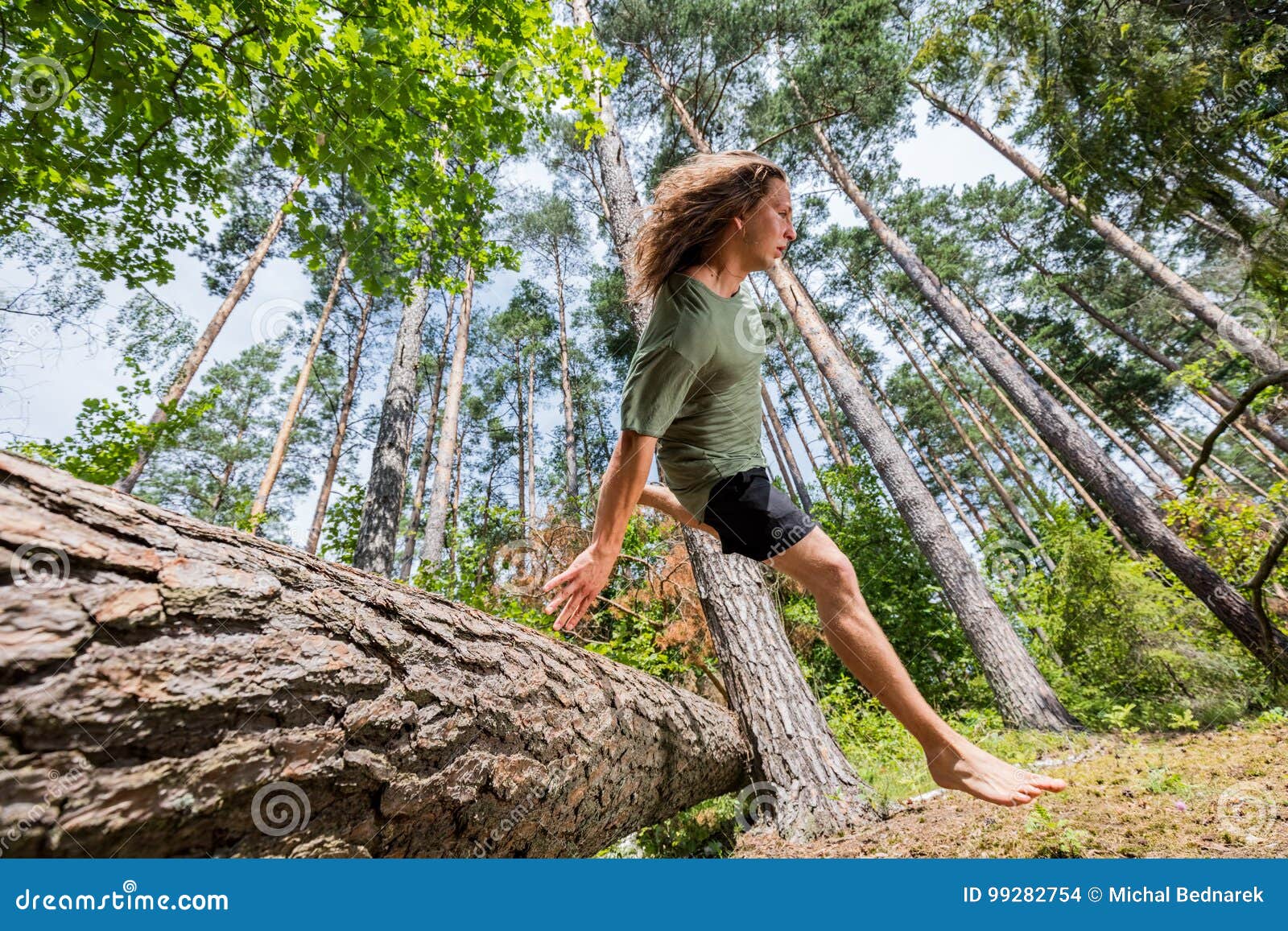 Young Man Jumping Over a Tree Trunk in the Forest. Stock Photo - Image ...