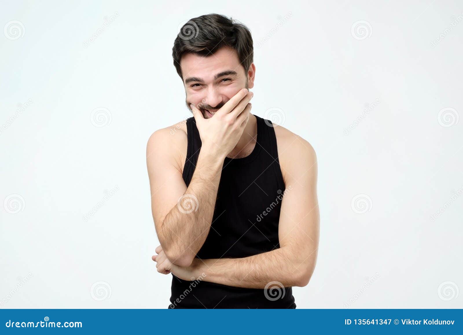 Young Man Laughing And Covering His Mouth With Hand Trying To Hold A