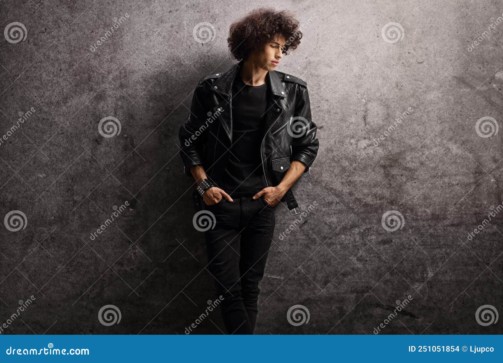 Young Man in a Leather Jacket Leaning on a Rugged Wall Stock Photo ...