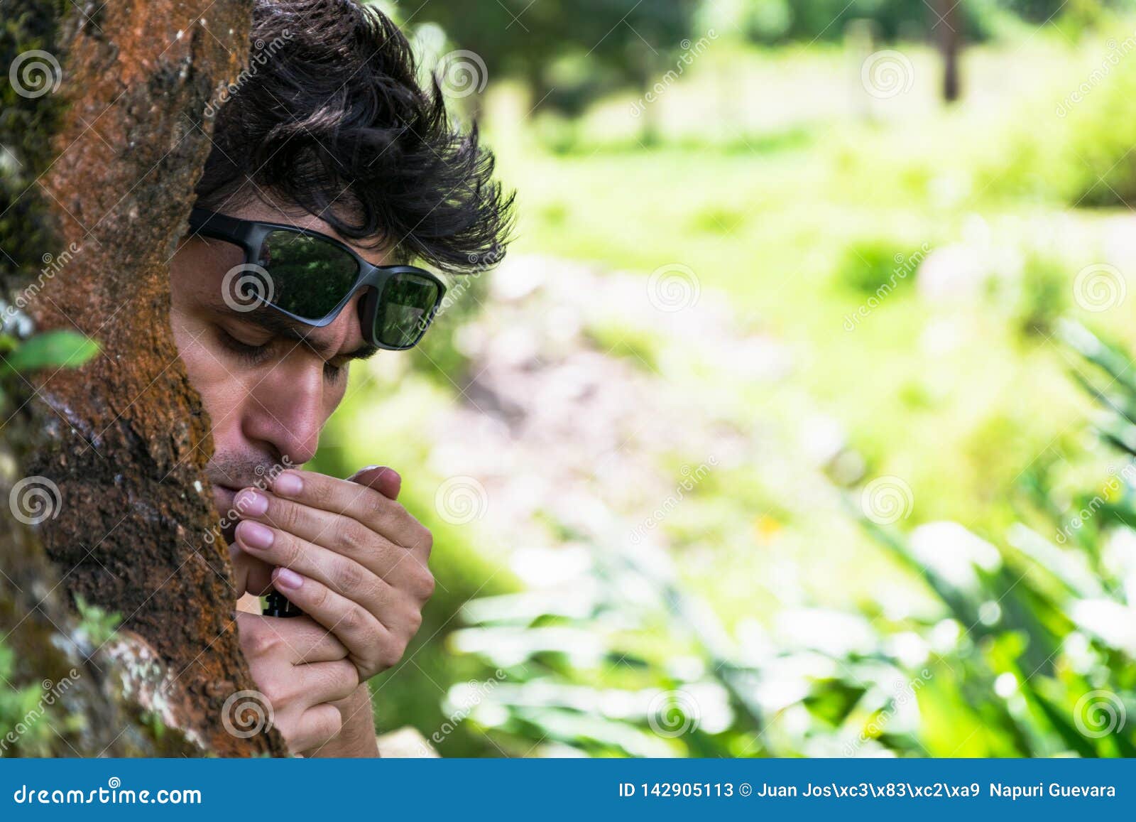 Young Man Lighting a Cigar Behind a Tree in a Forest Stock Image ...