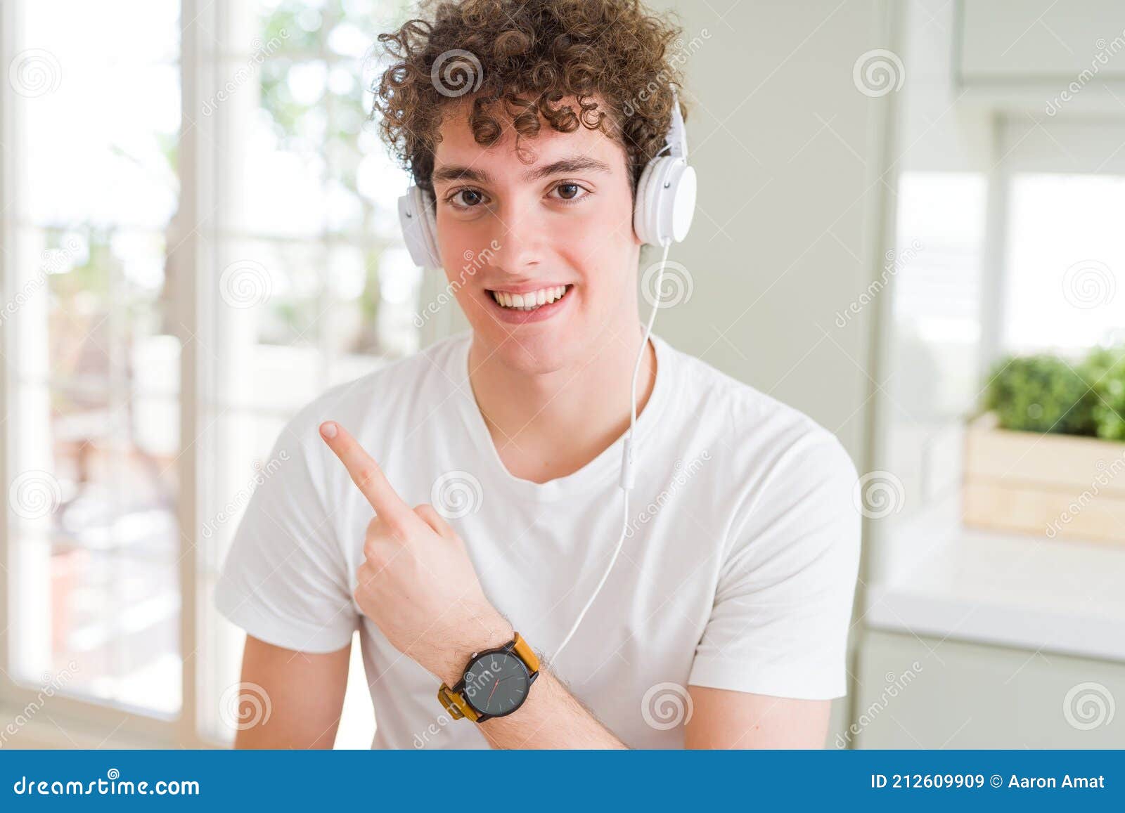 Young Man Listening To Music Wearing Headphones At Homes Cheerful With