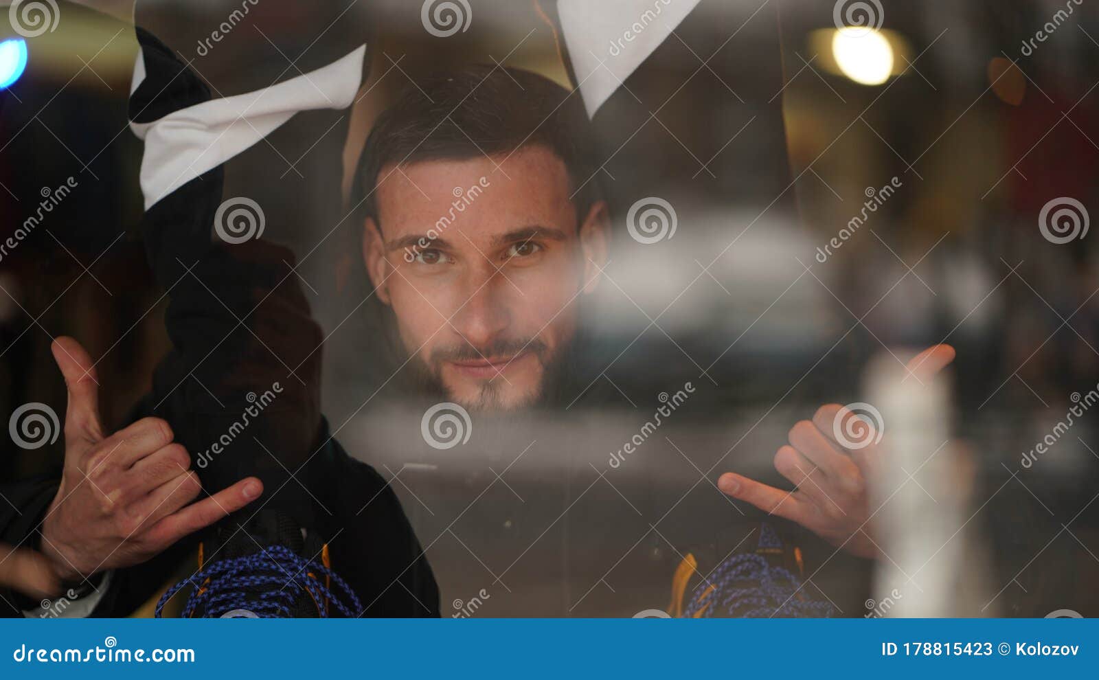 Young Man Look Seriously through Window at Street Gesturing with Both ...