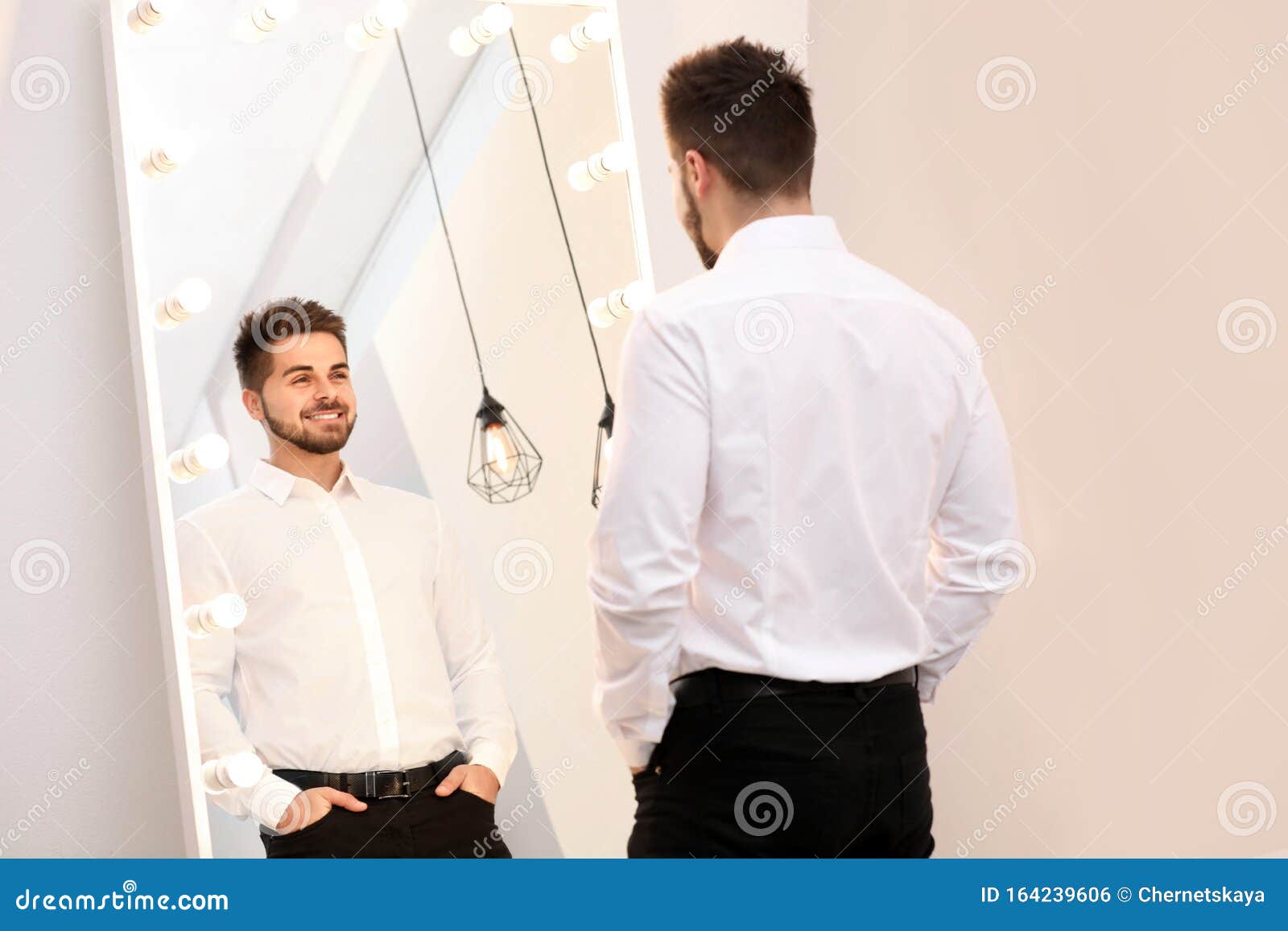 Young Man Looking at Himself in Large Mirror Stock Photo - Image of ...