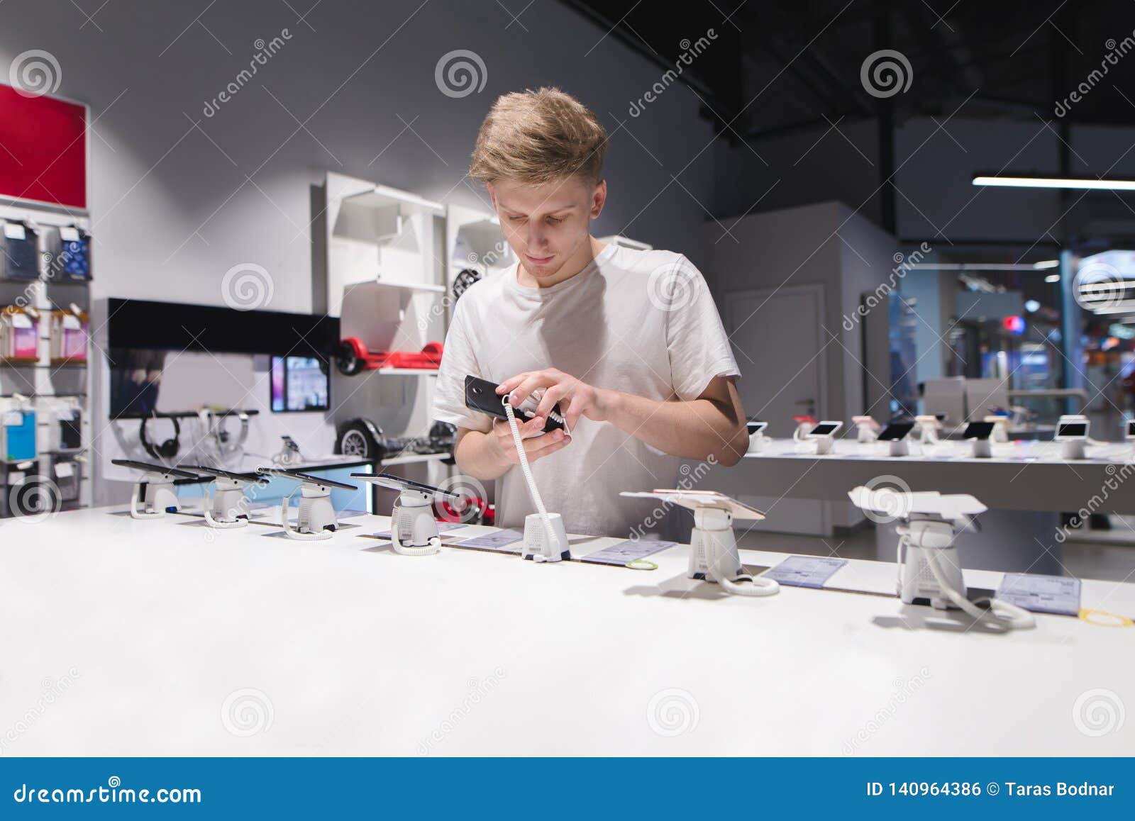 Young Man is Looking at a Smartphone in the Mobile Phone Department at ...