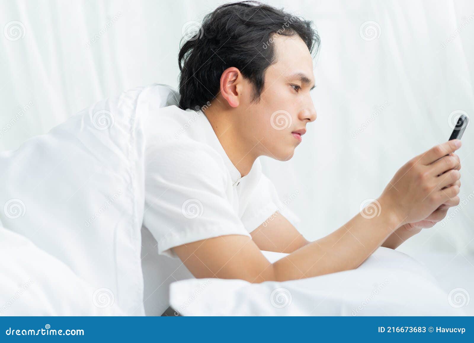 Young Man Lying in Bed Using a Phone Stock Image - Image of leisure ...