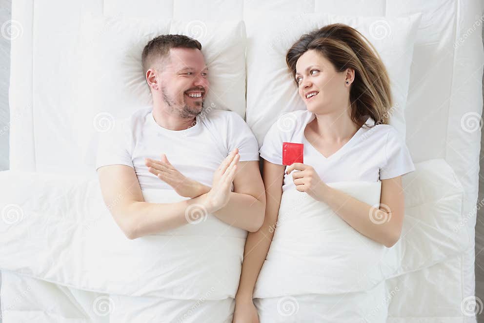 Young Man Lying In Bed With Woman And Refusing Condom Top View Stock