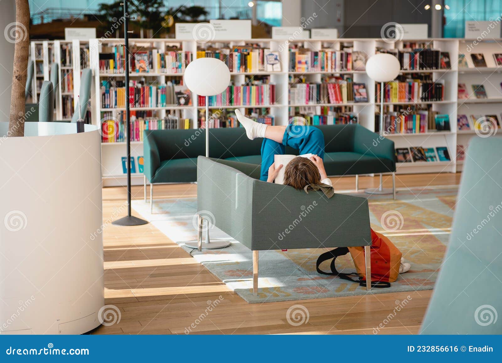 Young Man Lying on the Sofa in the Library and Reading a Book. Stock ...
