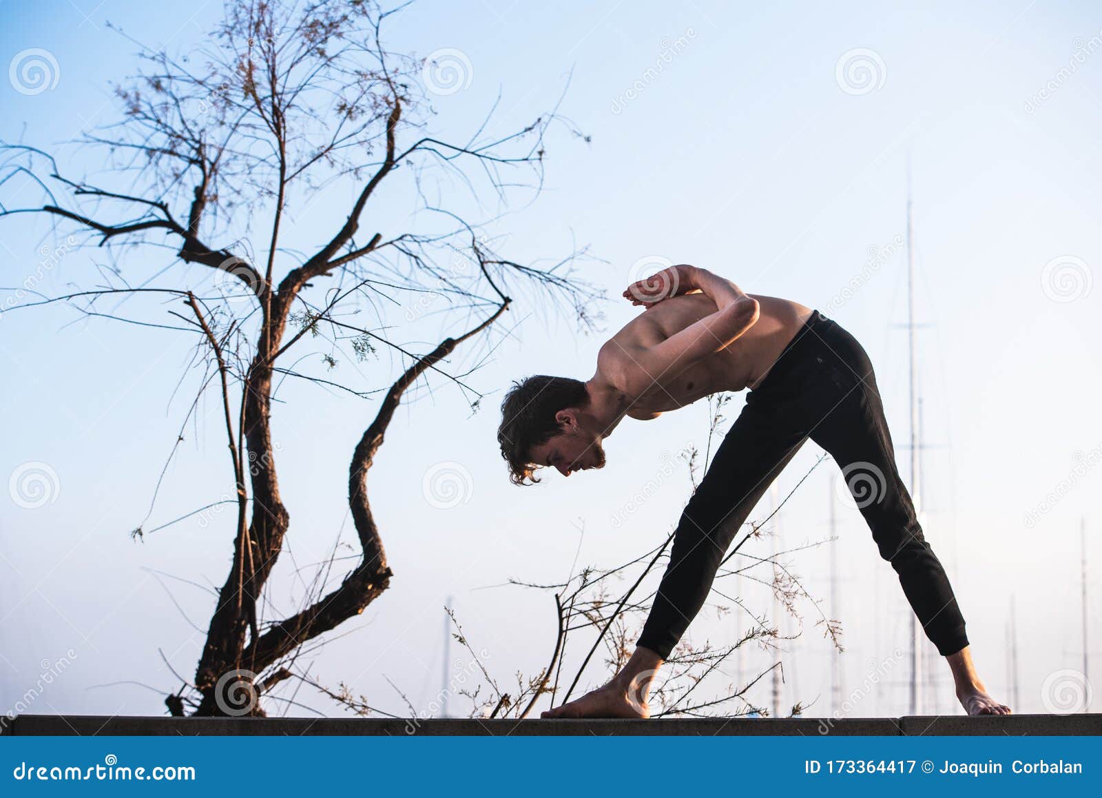 Young Man Performing Joint Movement Exercise Inspired by Yoga, Outdoors ...