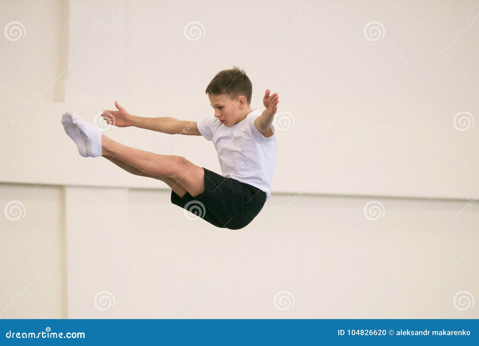 The Young Man Performs Gymnastic Exercises in the Gym. Stock Photo ...