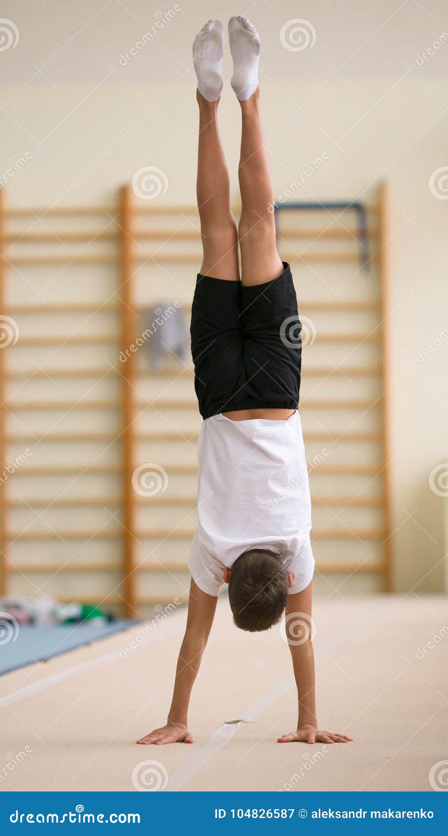 The Young Man Performs Gymnastic Exercises in the Gym. Stock Image ...