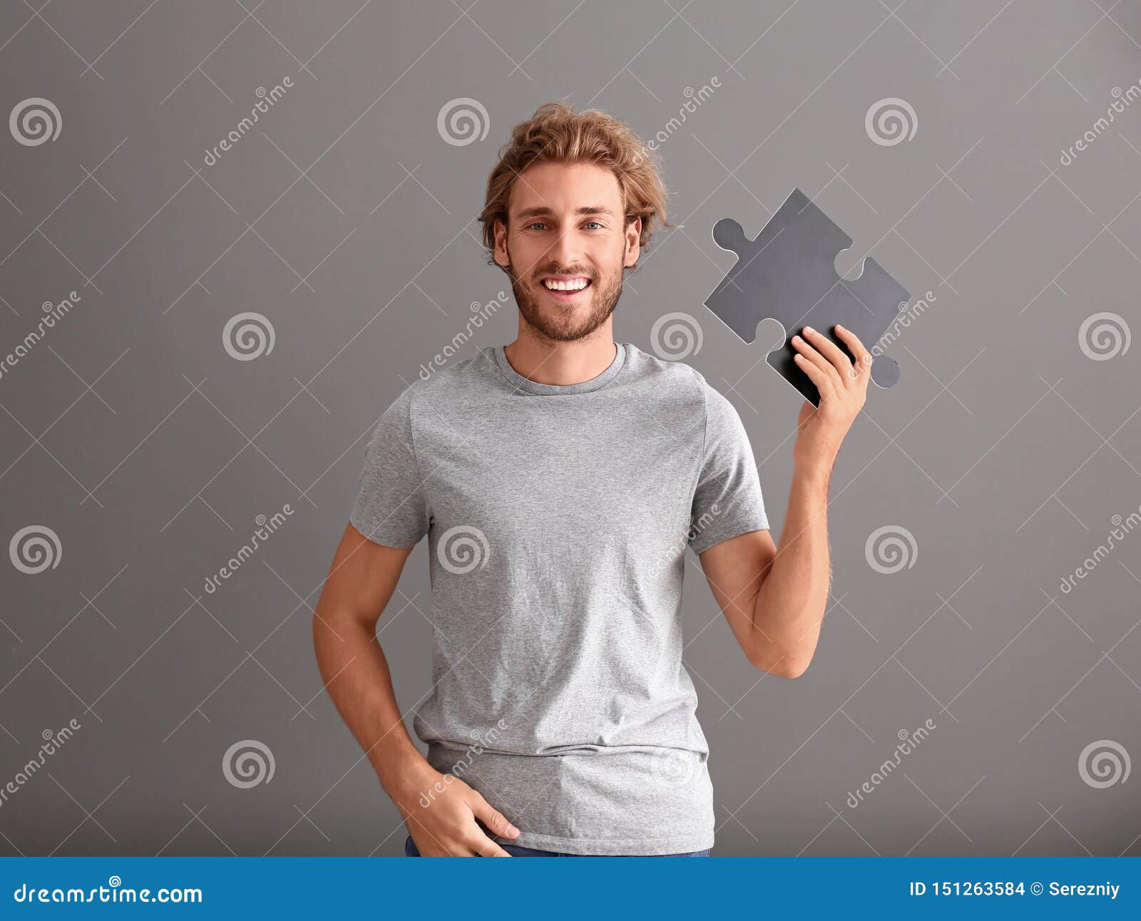 Young Man with Piece of Jigsaw Puzzle on Grey Background Stock Photo ...