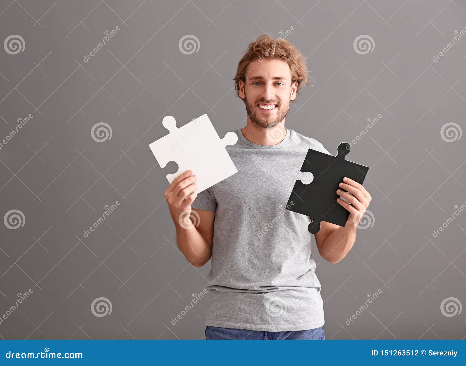 Young Man with Pieces of Jigsaw Puzzle on Grey Background Stock Photo ...