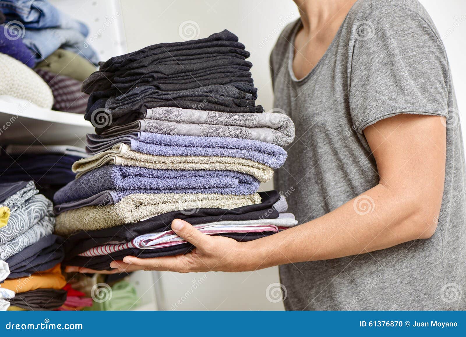 Young Man with a Pile of Folded Clothes Stock Photo - Image of season ...