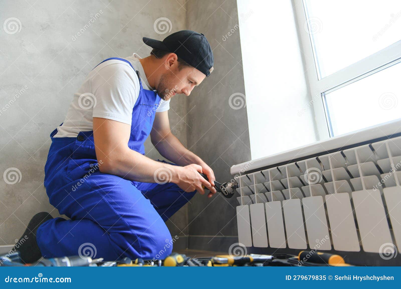 Young Man Plumber Checking Radiator while Installing Heating System in ...