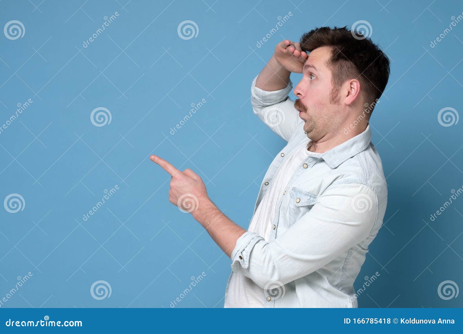 Young Man Pointing, Surprised by Something or Someone, Isolated on Blue ...