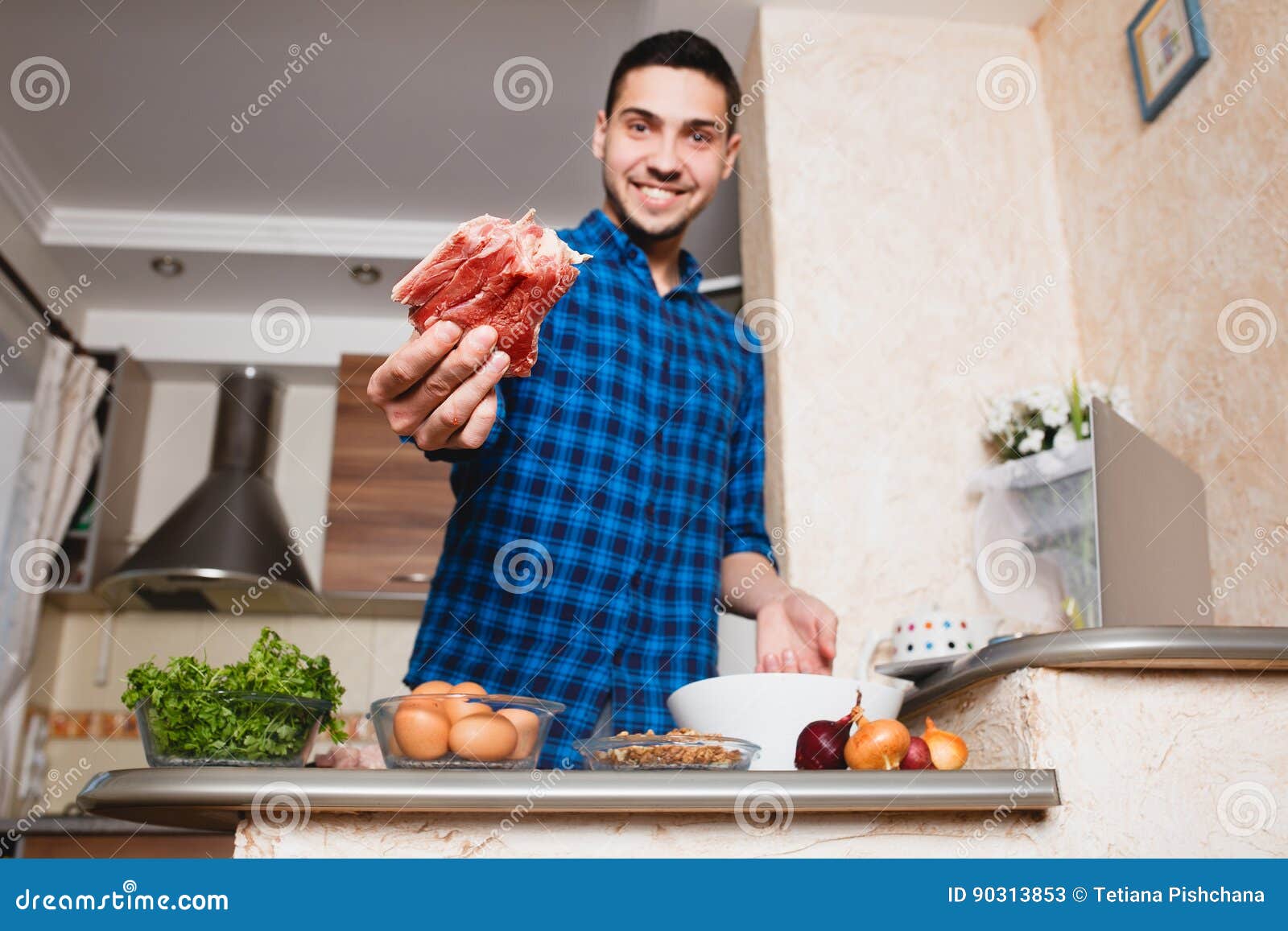 Young Man Preparing Meat in Her Kitchen , Looking into the Frame Stock ...