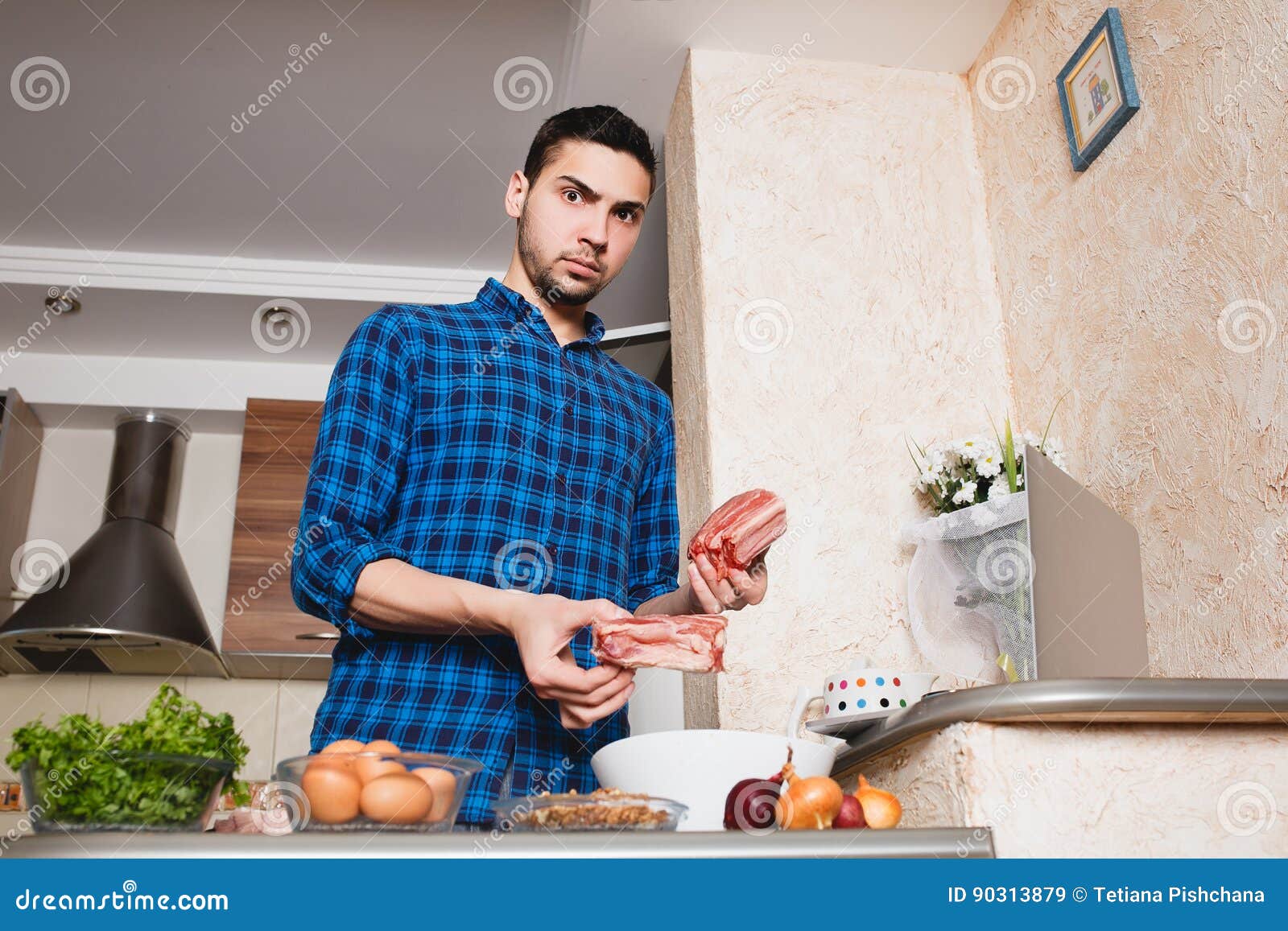 Young Man Preparing Meat in Her Kitchen , Looking into the Frame Stock ...