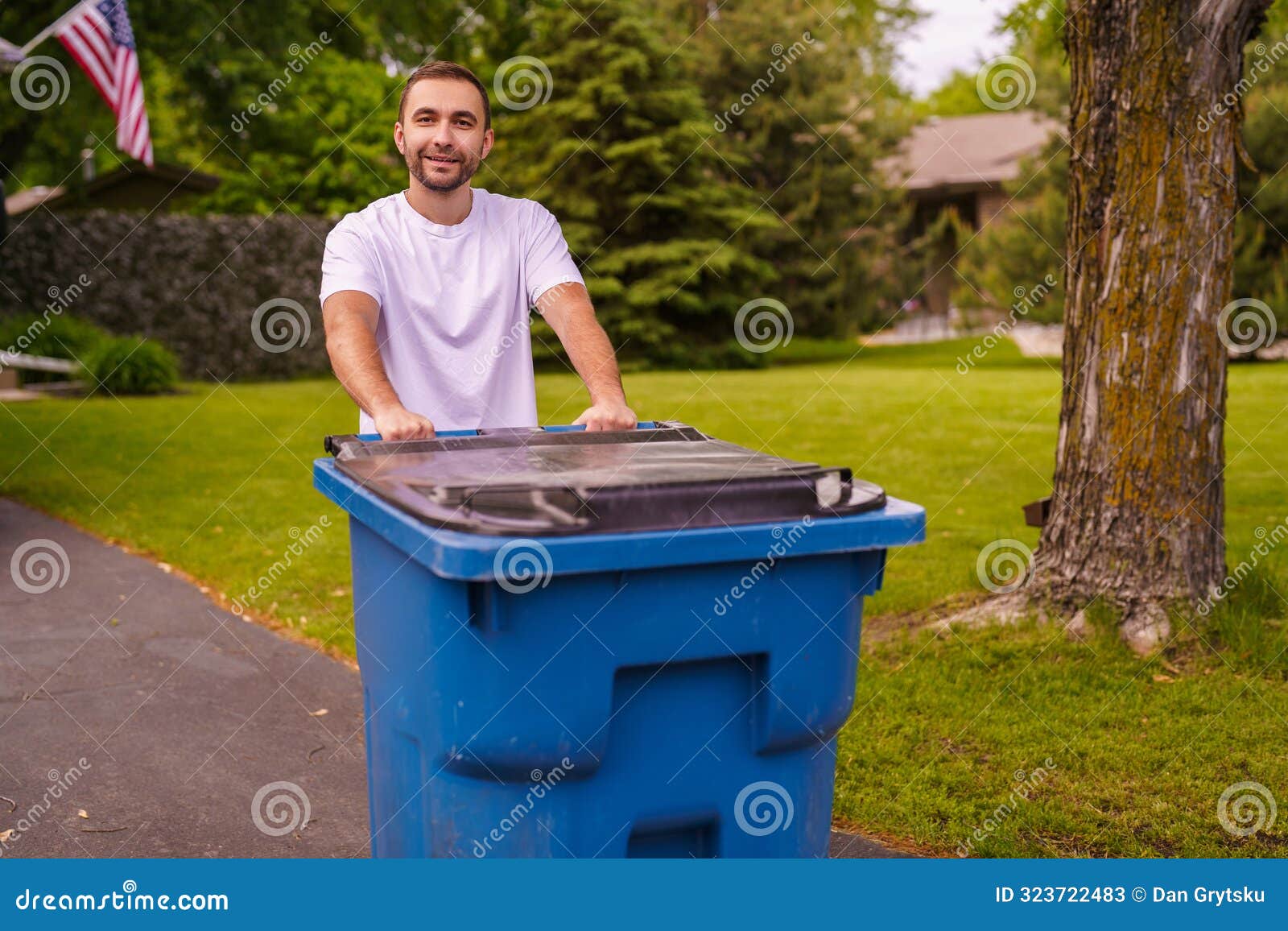 Young Man Pushes a Large Green Plastic Trash Bin for Weekly Waste ...