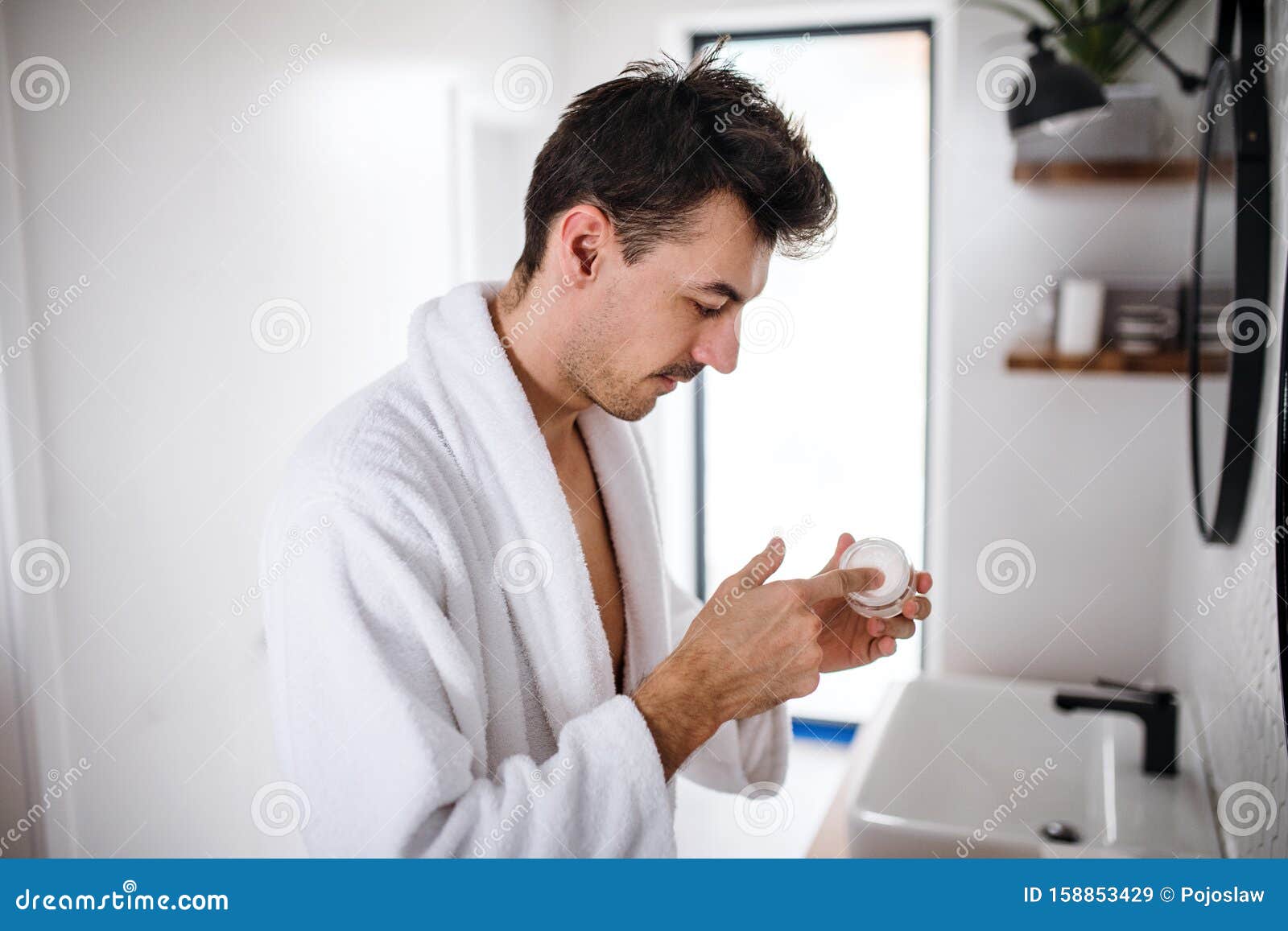 Young Man Putting Cream on Face in the Bathroom in the Morning, daily ...
