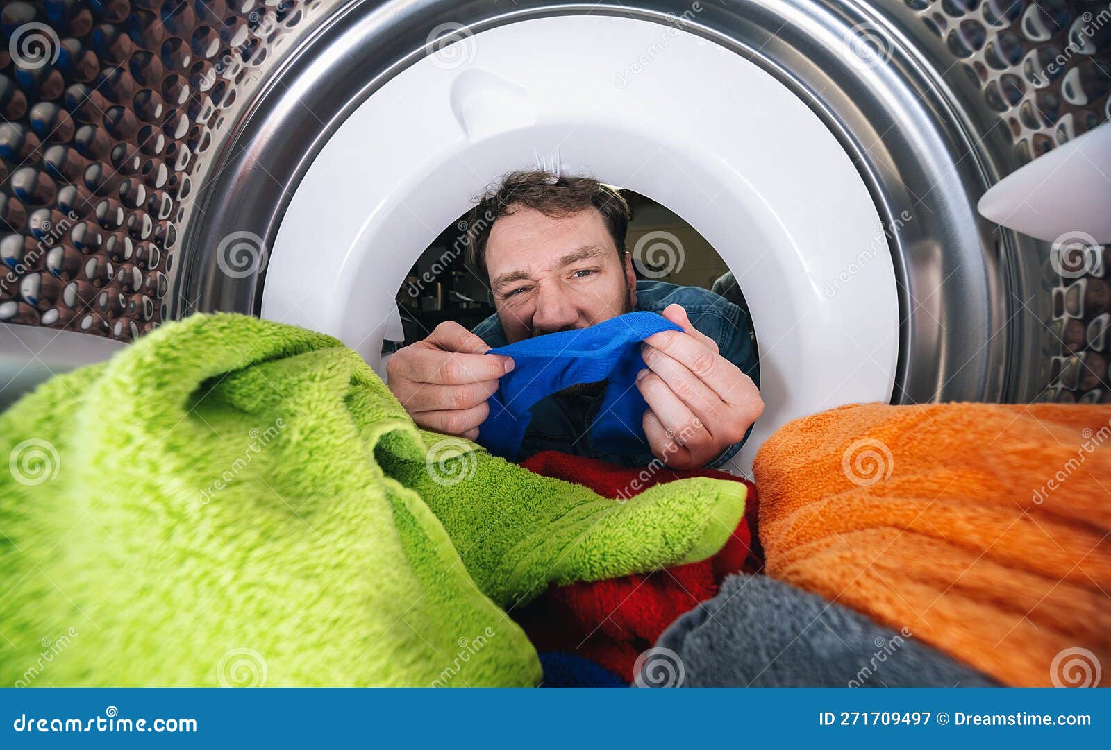 Young Man Reaching Inside a Washing Machine or Dryer Doing Laundry View ...