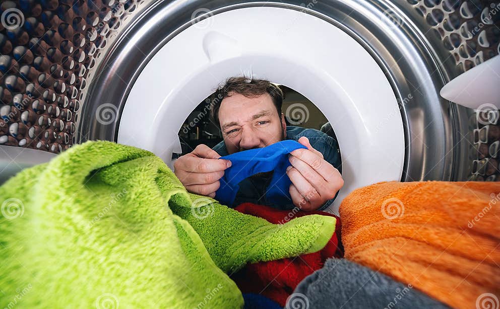Young Man Reaching Inside a Washing Machine or Dryer Doing Laundry View ...