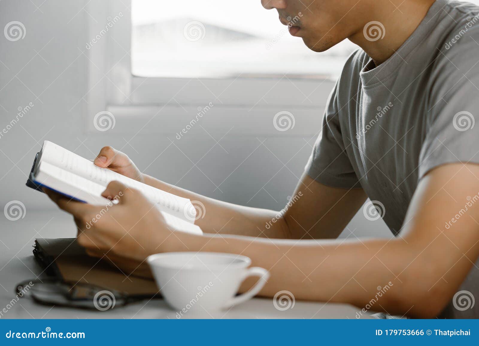 Young Man Reading Book at Work Desk in Free Time from Working at Home ...