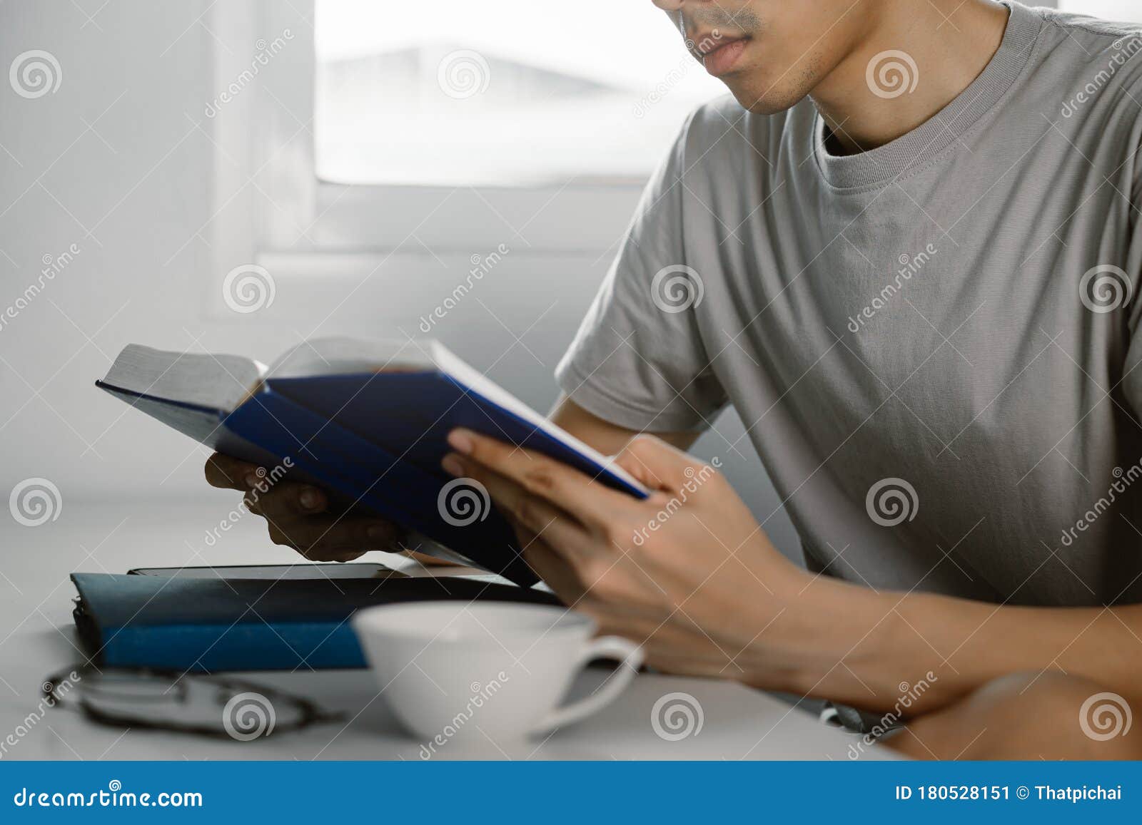Young Man Reading Book at Work Desk in Free Time from Working at Home ...